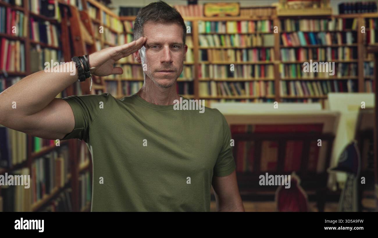 Young caucasian man salutes right hand to forehead in library ...