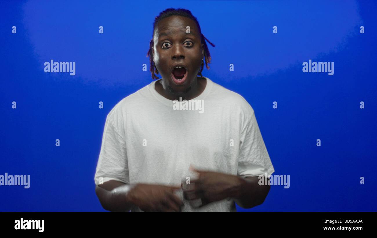 Man with hands on cheeks and open mouth gesturing in studio with blue ...