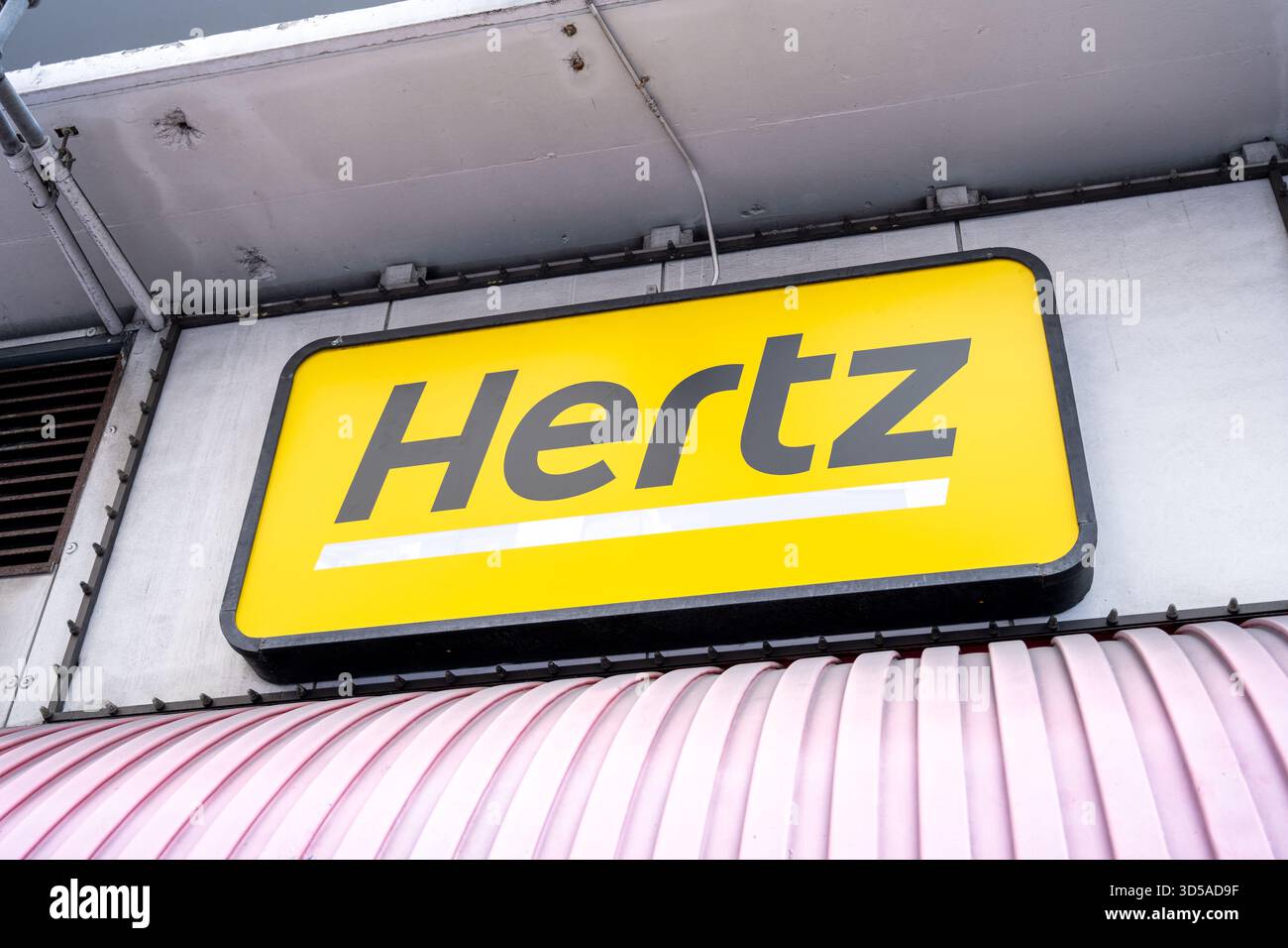 Hertz car rental sign on yellow panel above ribbed pink awning, San ...