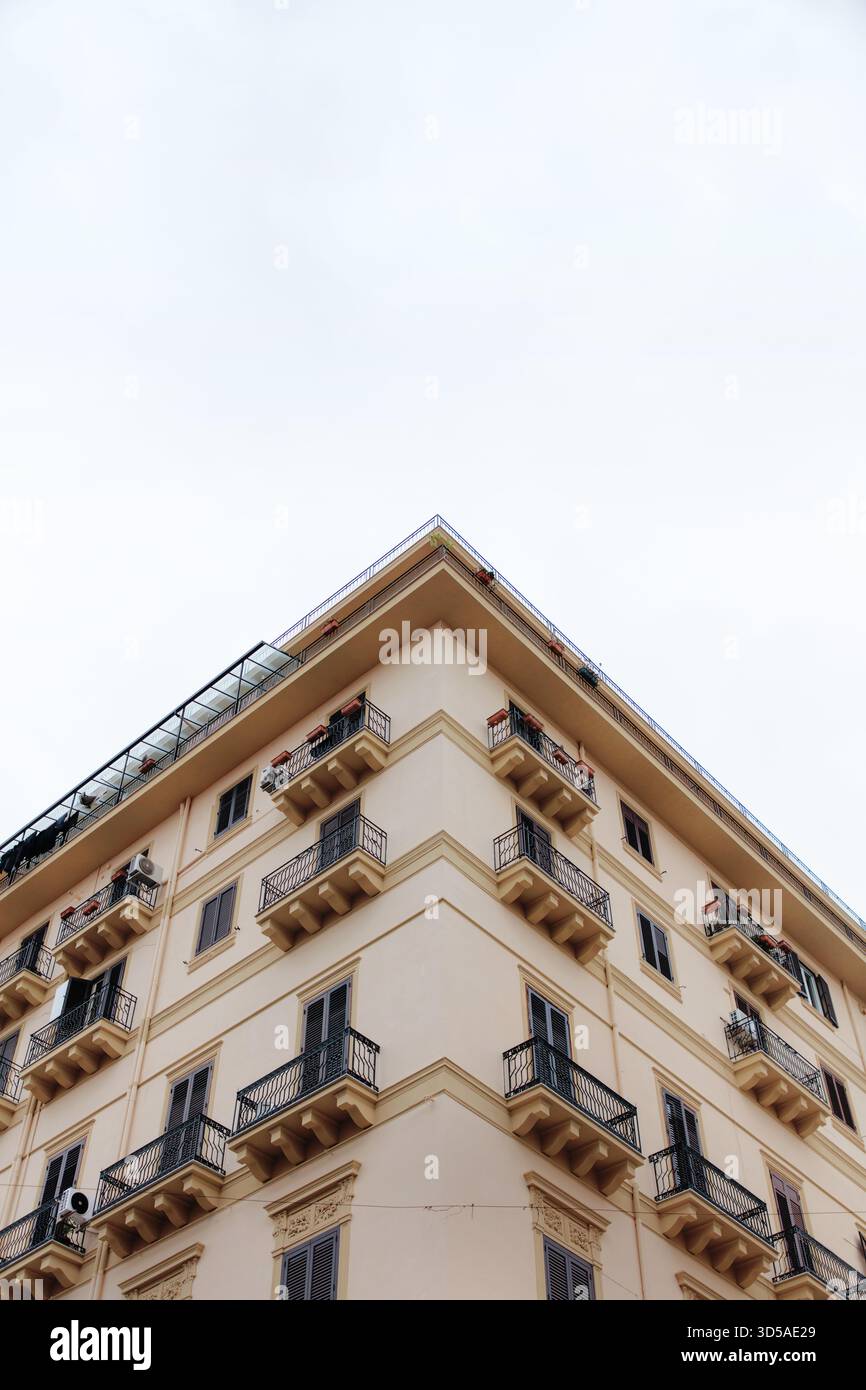 An angled view of a pale beige apartment building featuring multiple ...