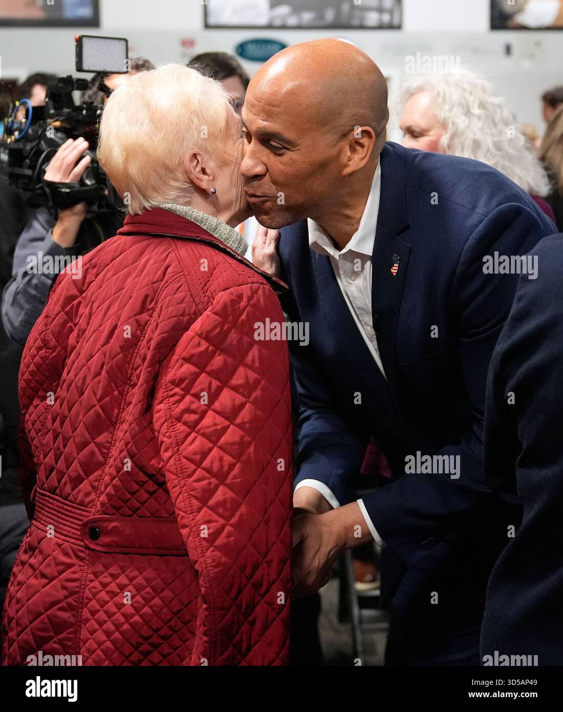 Sen. Cory Booker, D-N.J., kisses a guest on the cheek during a ...