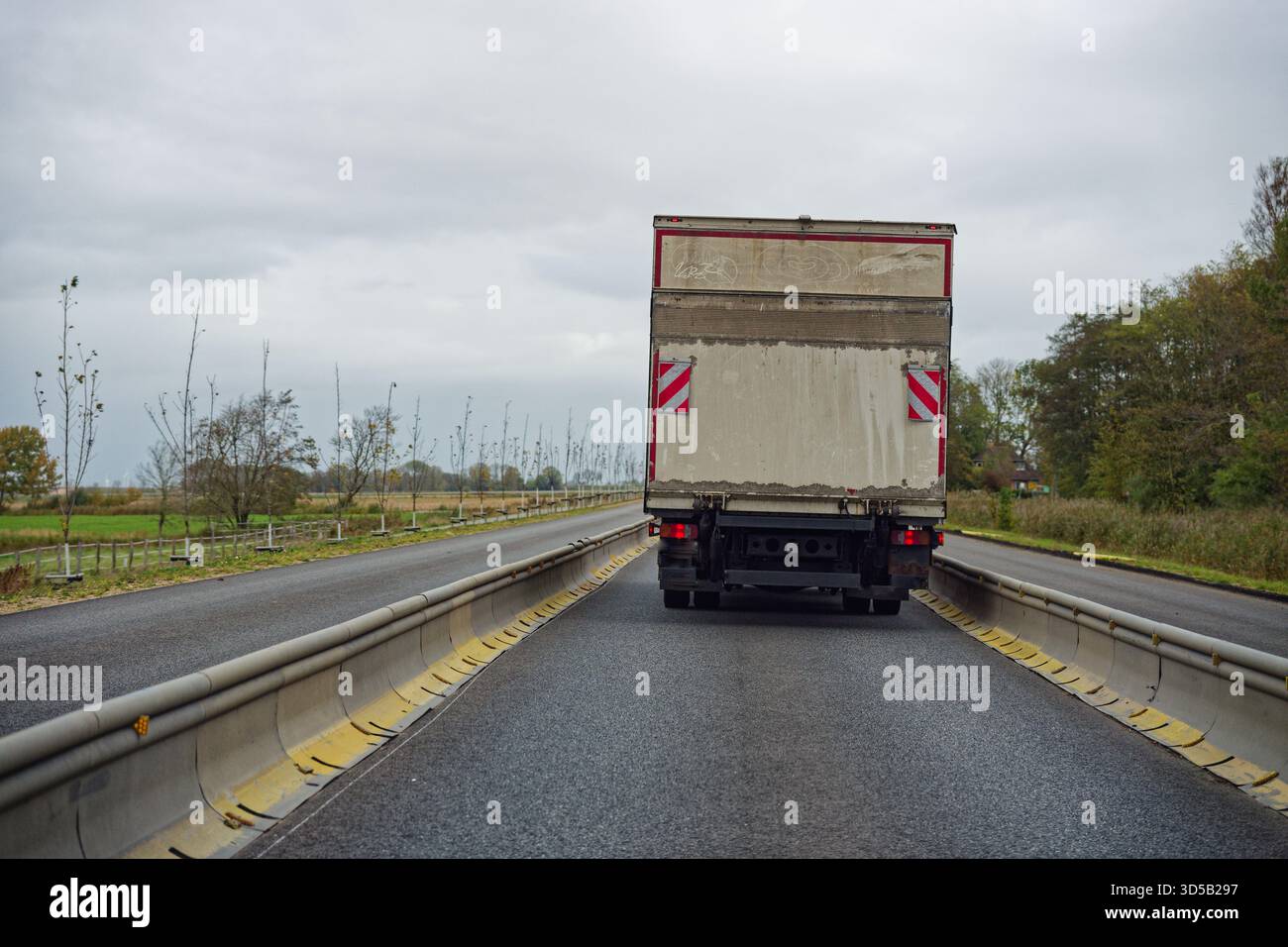 A heavy truck moves along a straight road between low temporary ...