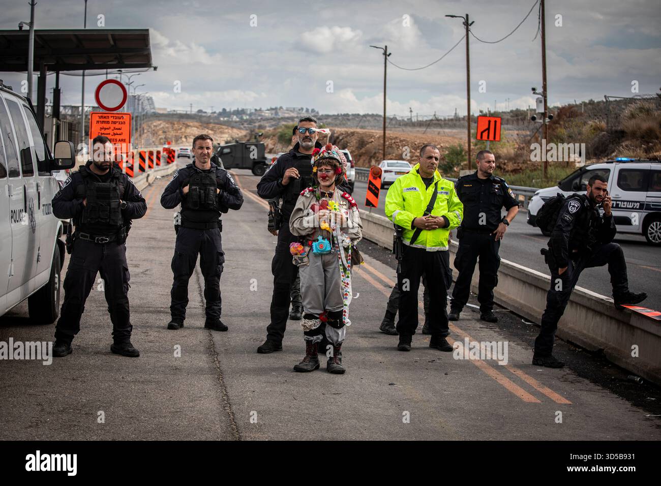 An Israeli activists dressed as a clown stands infant of police ...