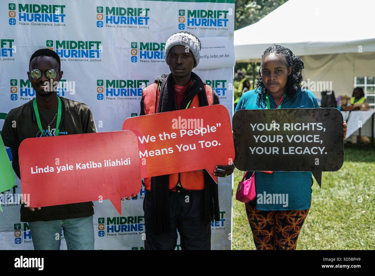 Participants pose for a photo while holding posters during a continuous ...