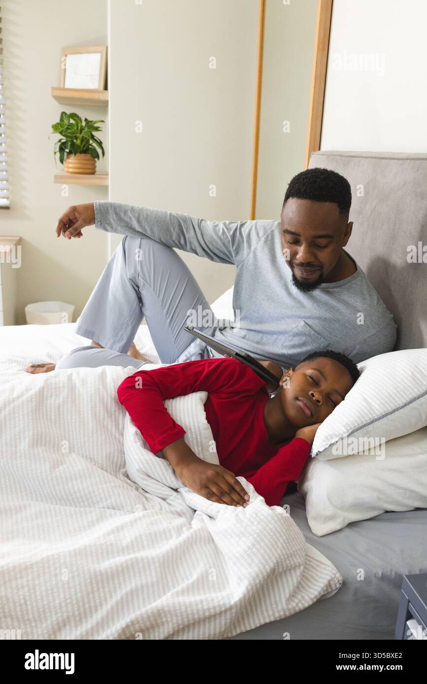 Father waking up son in bed, gently smiling and enjoying morning ...