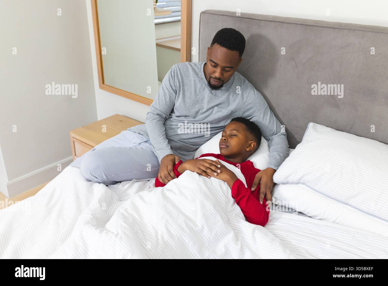 Father comforting son in bed, sharing tender moment at home Stock Photo ...
