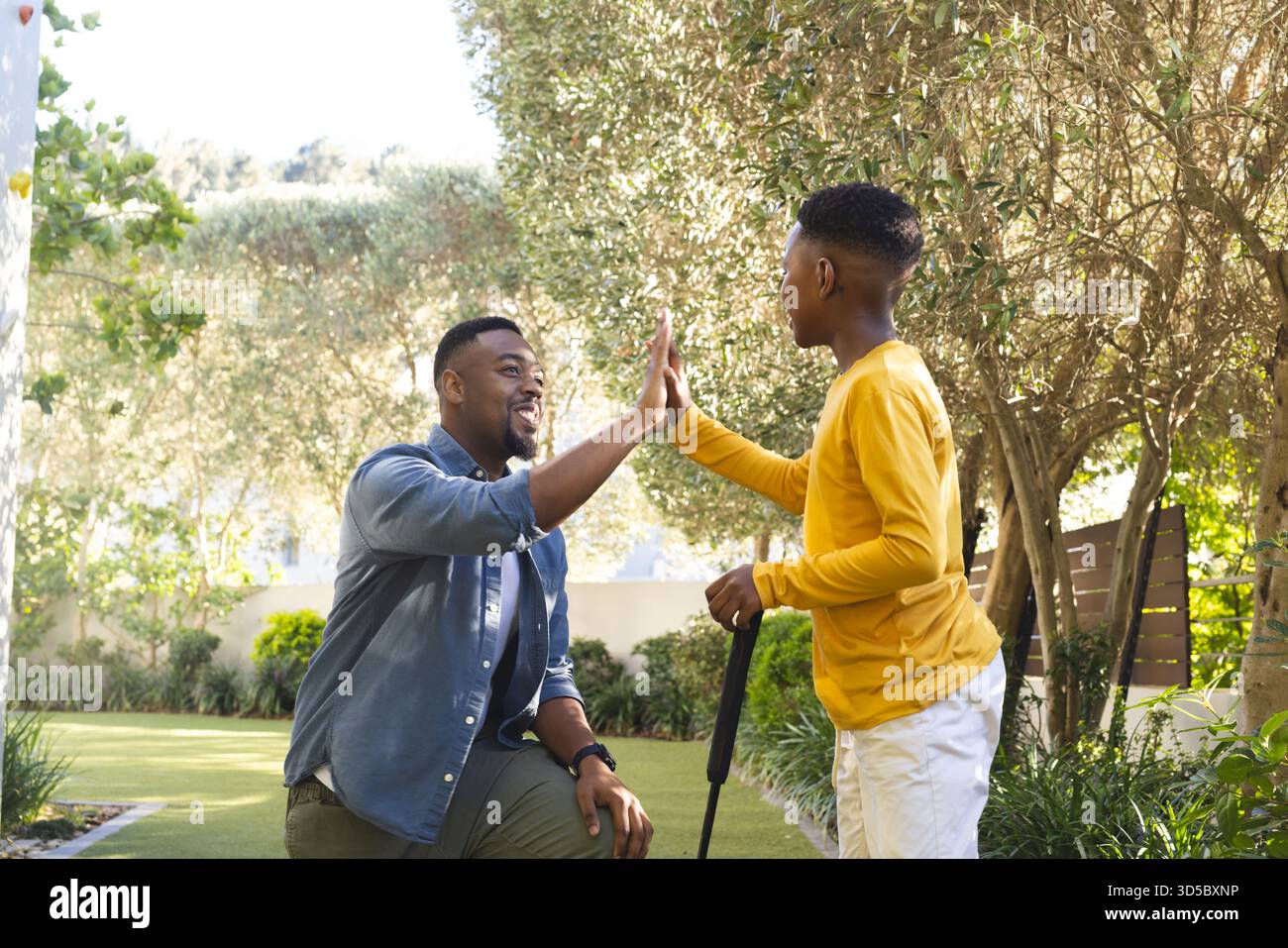 African American father and son playing mini golf in backyard garden ...