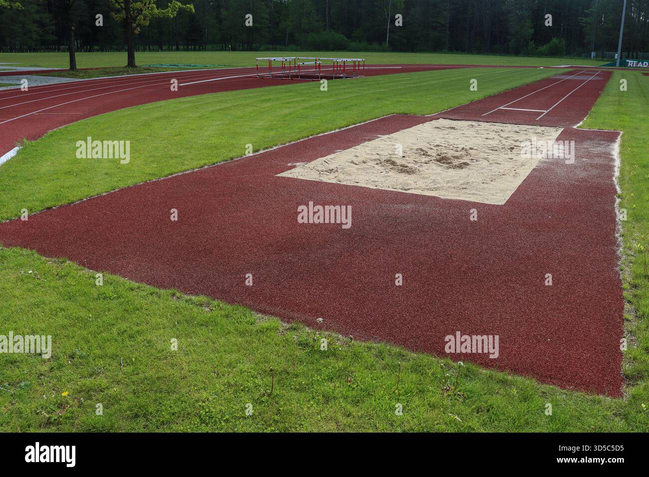 An empty jumping pit with shoe prints on a green grass stadium. Track ...