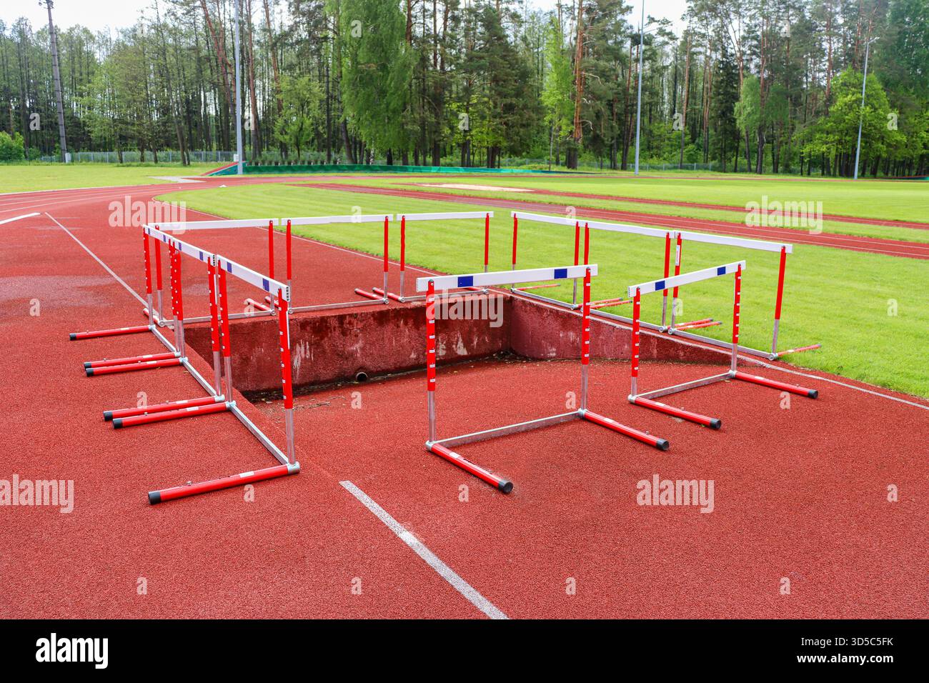 Portable track and field hurdles block off a pit on the stadium's red ...