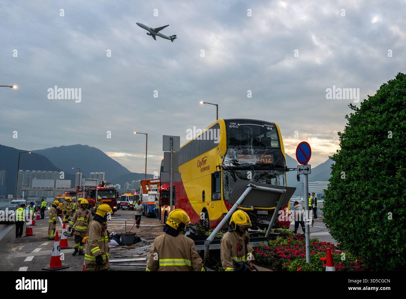 A plane taking off from the airport flying over a double decker bus ...