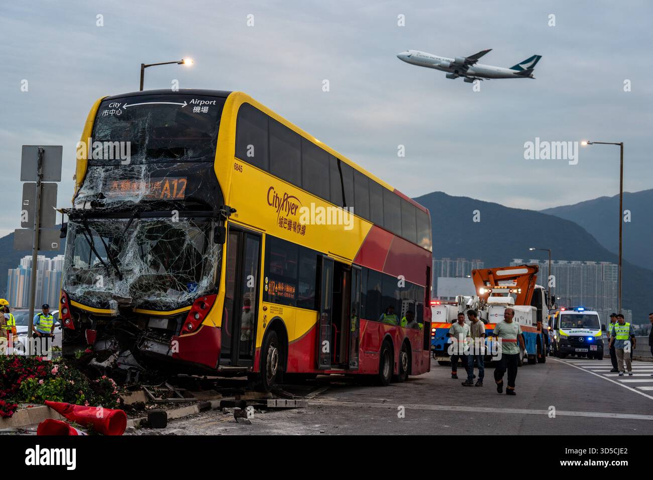 A plane taking off from the airport flying over a double decker bus ...