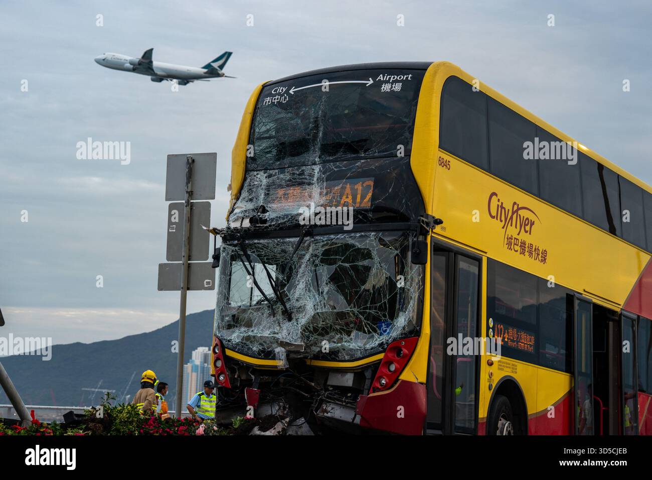 A plane taking off from the airport flying over a double decker bus ...
