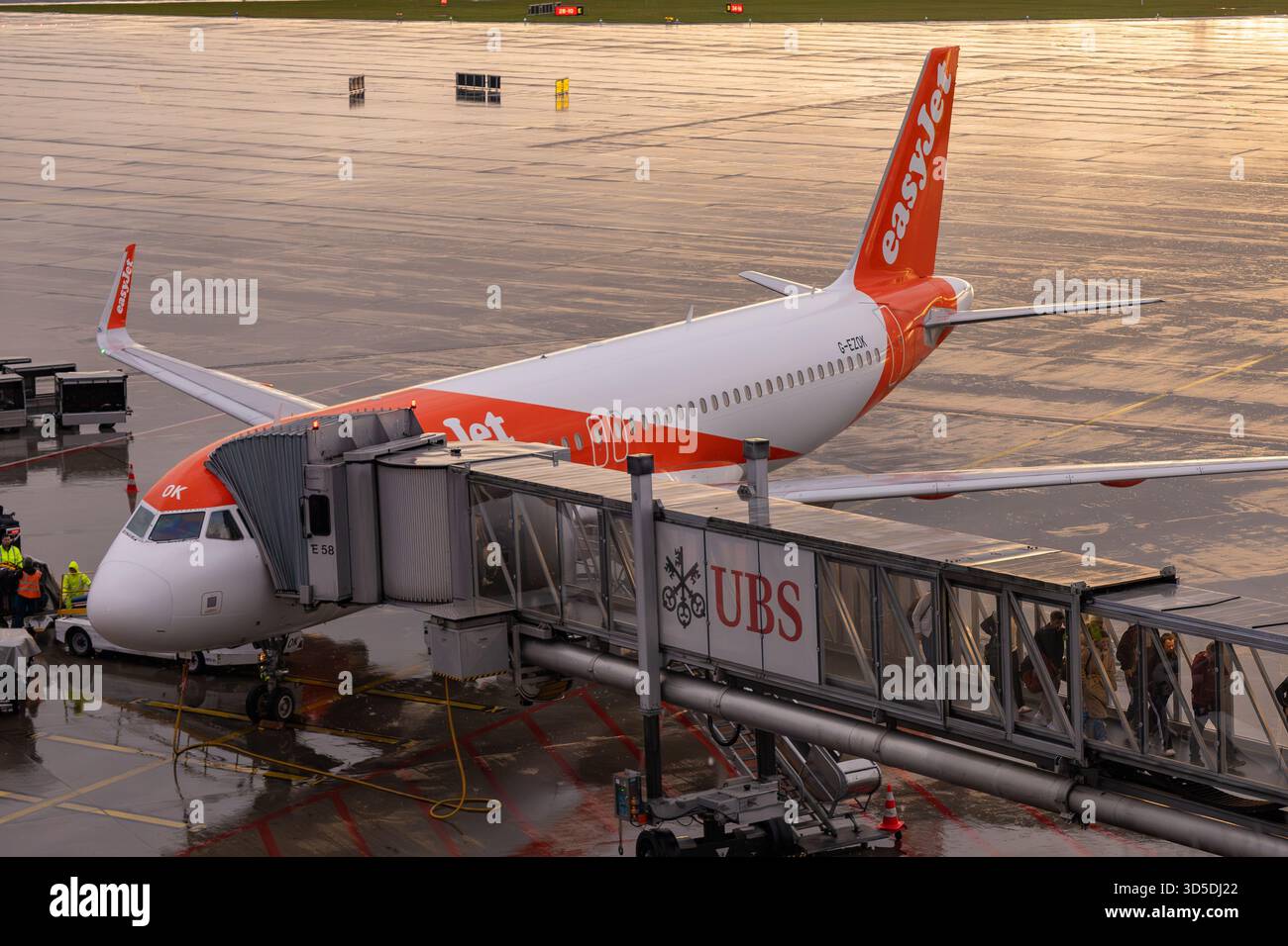 easyJet Airbus A320 parked at an airport gate with a passenger boarding ...