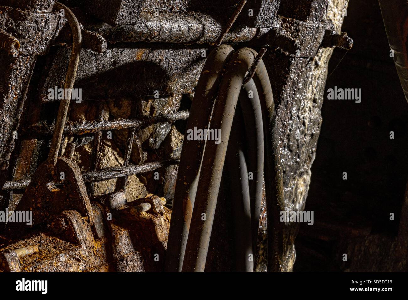 Heavy tools and equipment inside an underground mine, with steel chains ...