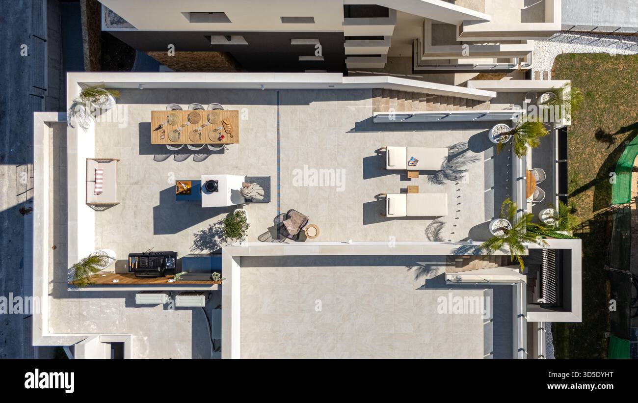 Modern rooftop terrace featuring sun loungers, dining table, barbecue ...