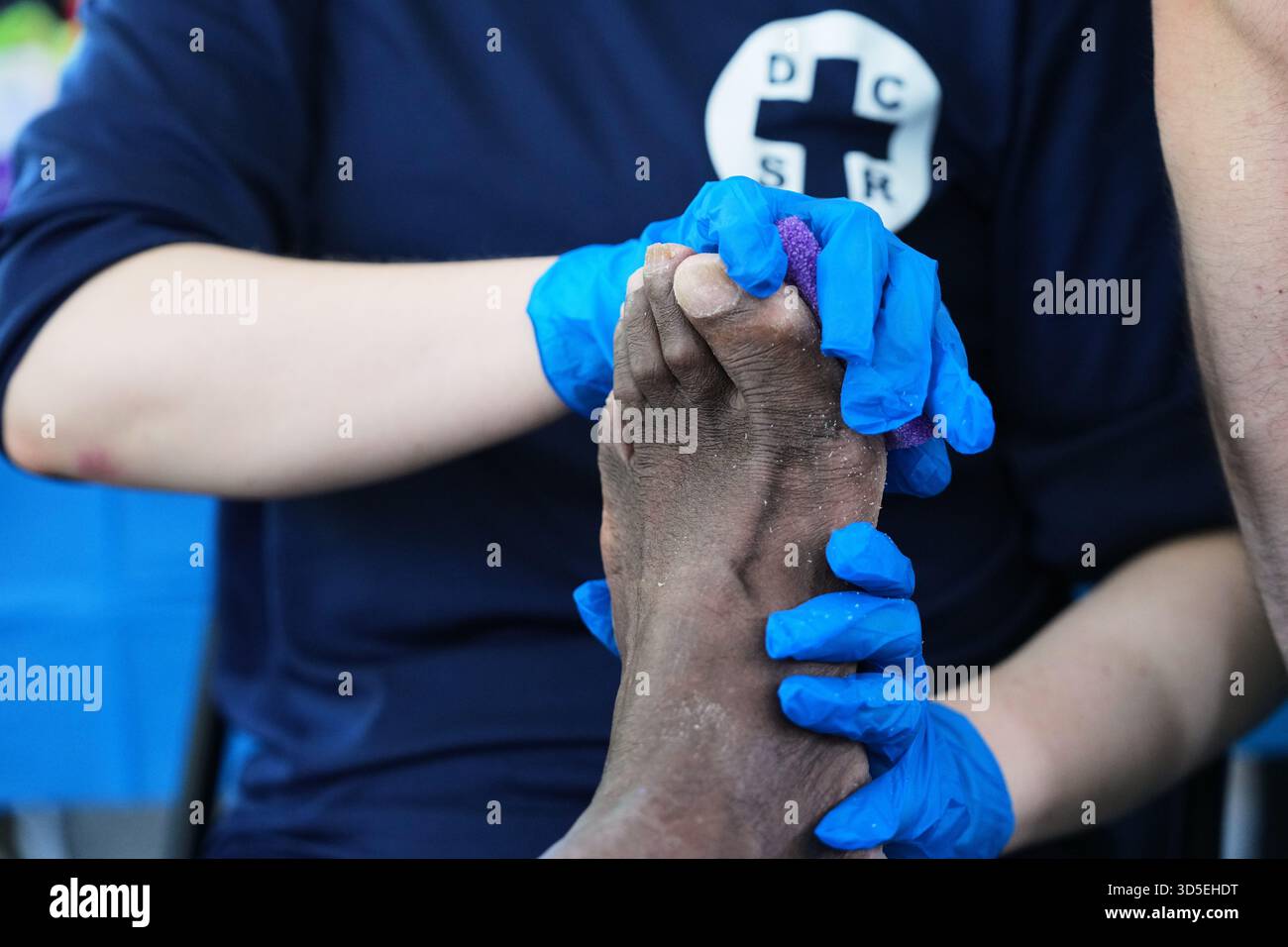 Dennis Phillips has his feet cleaned during a community foot washing ...