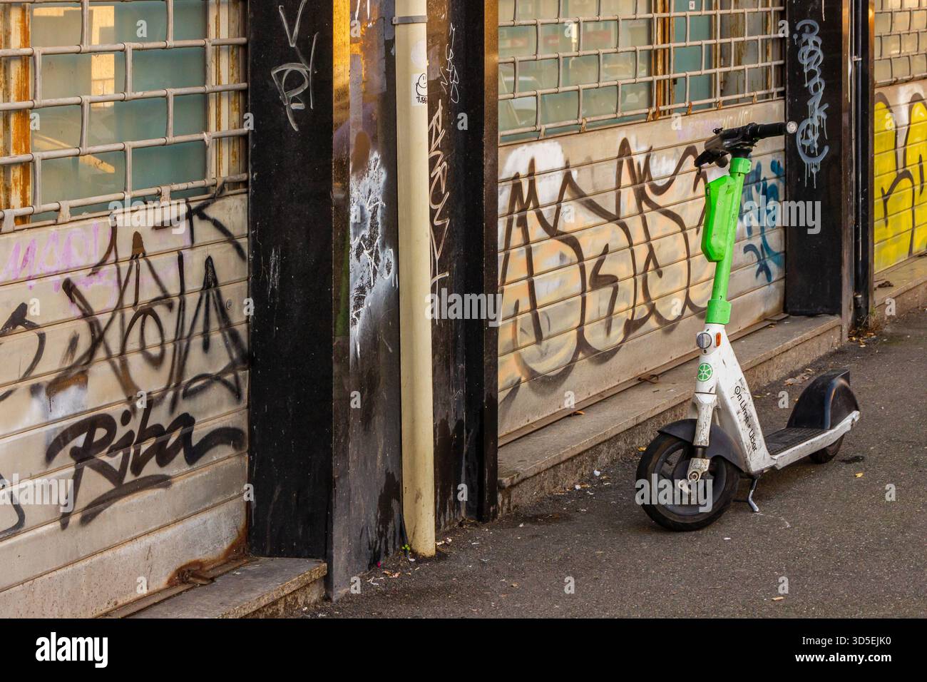 Urban Graffiti Wall and Green Electric Scooter Parked Along Shuttered ...