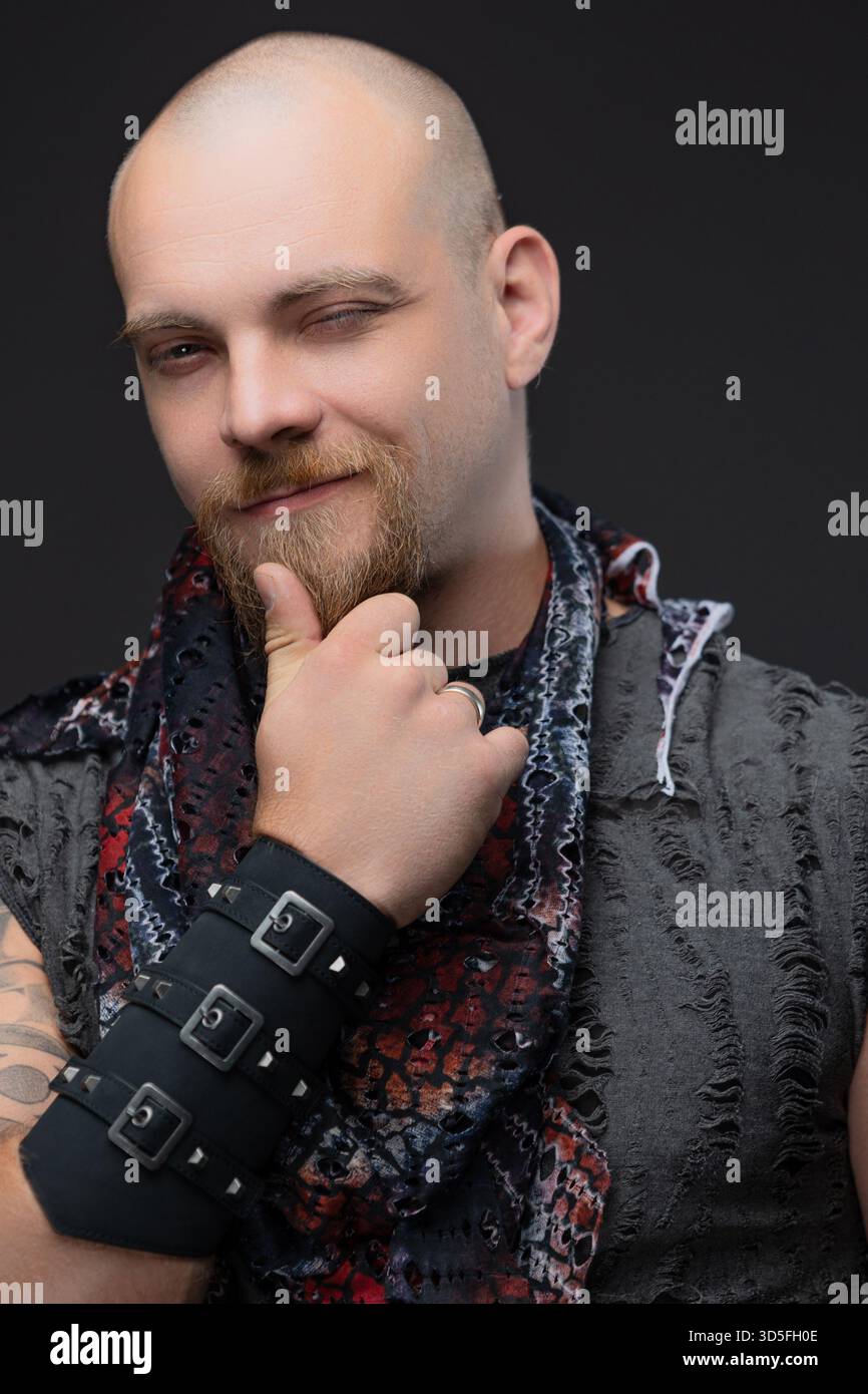 Bald male model in edgy suit accessorized with handcuffs on neutral ...