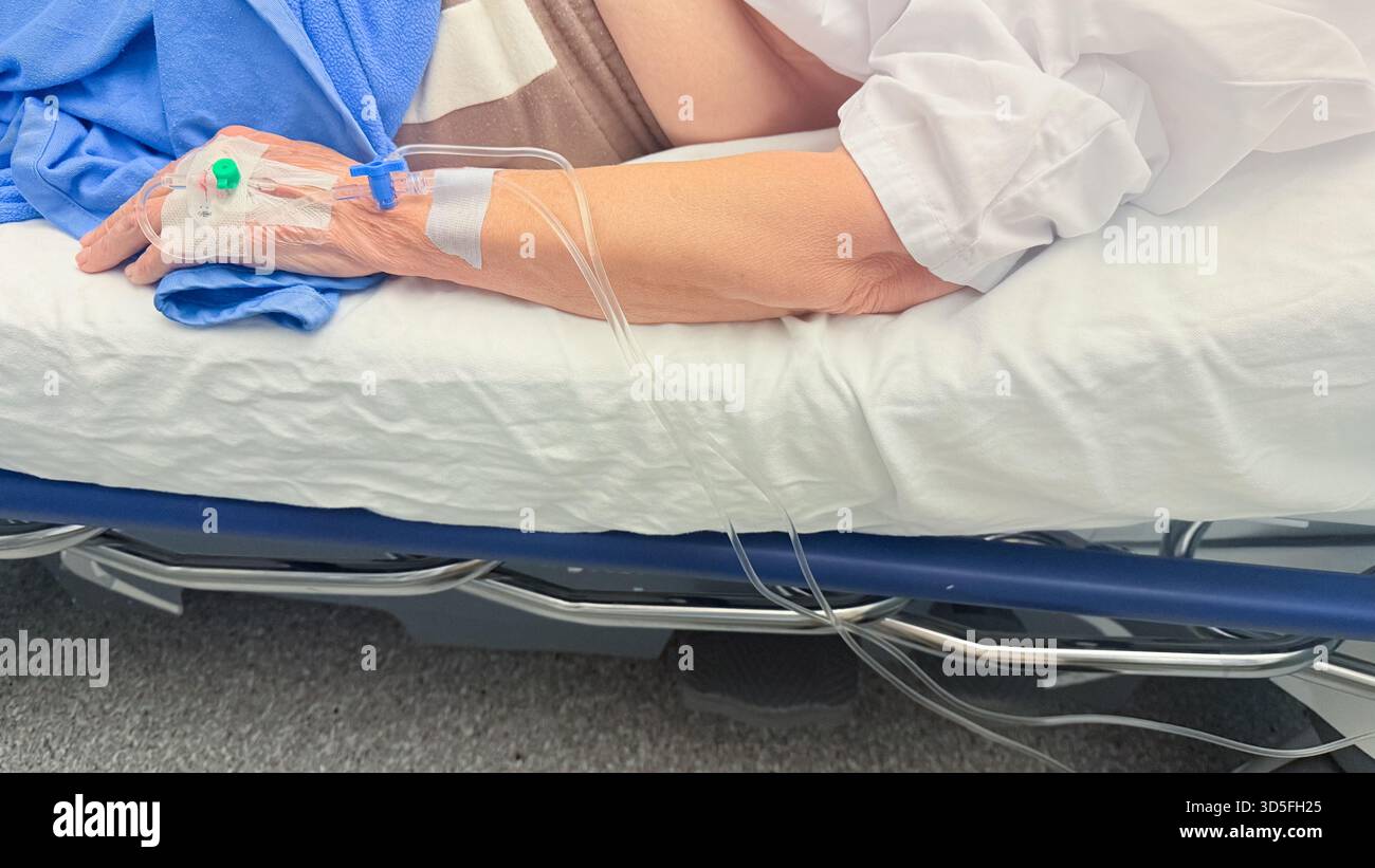 Patient Lying On Hospital Bed With Intravenous IV Line Attached To Hand ...