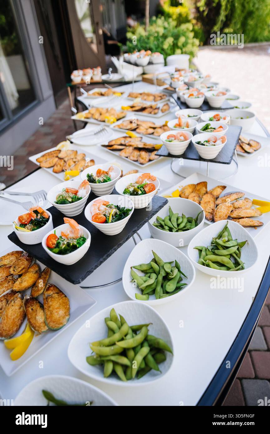 Catering buffet with edamame bowls, shrimp salads, and baked mussels ...