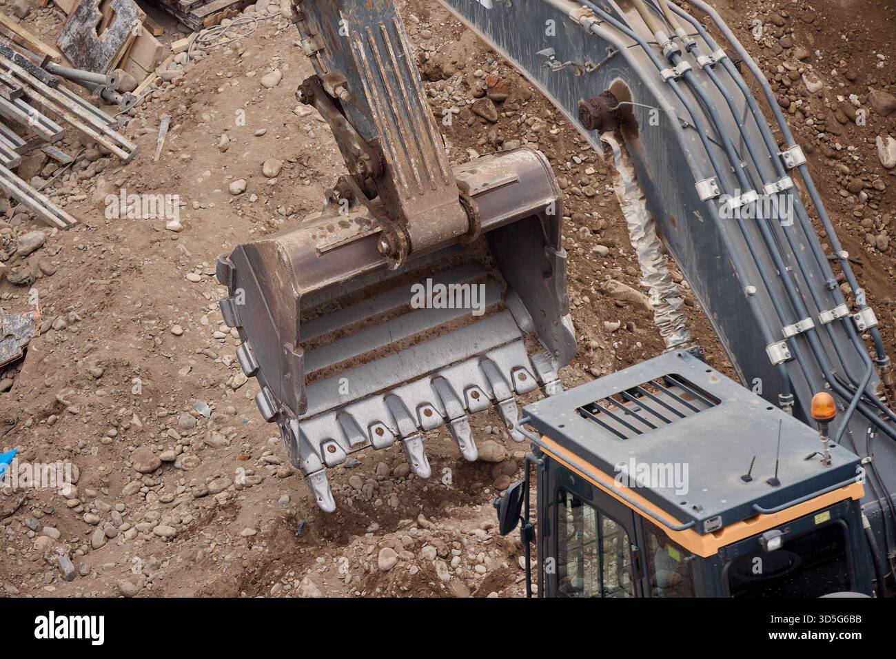 Excavator bucket digging into soil during construction work, showing ...
