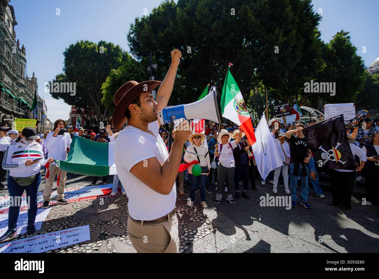 Young speaker using a megaphone to address the crowd, raising his fist ...