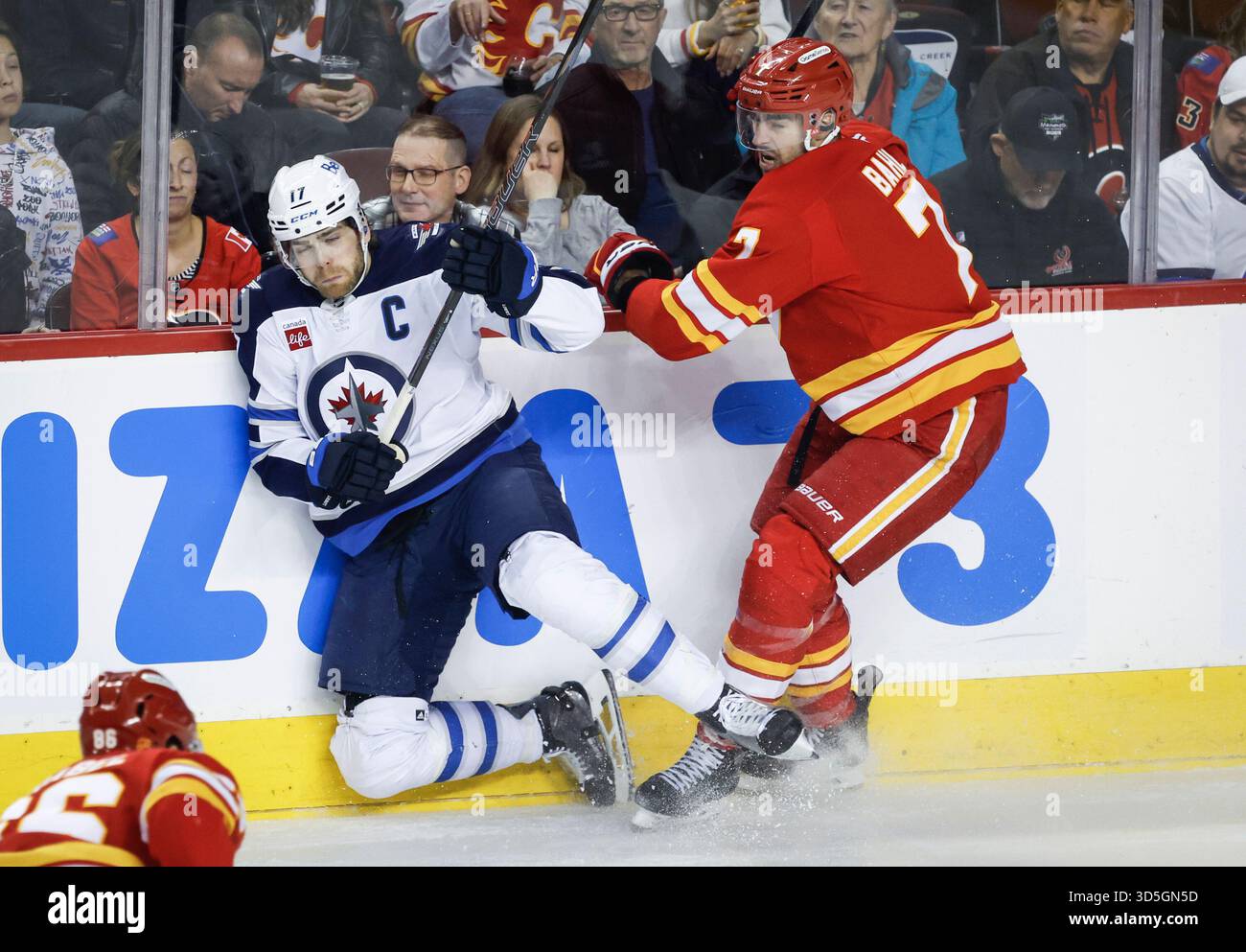 Winnipeg Jets' Adam Lowry (17) is checked by Calgary Flames' Kevin Bahl ...