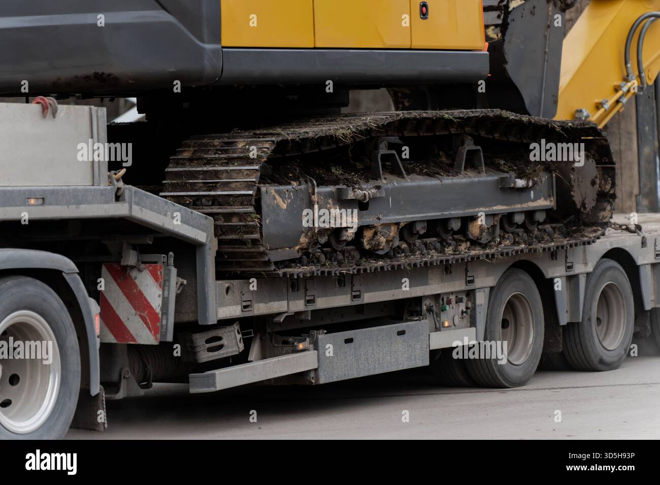 Heavy construction machine with steel tracks loaded onto long platform ...