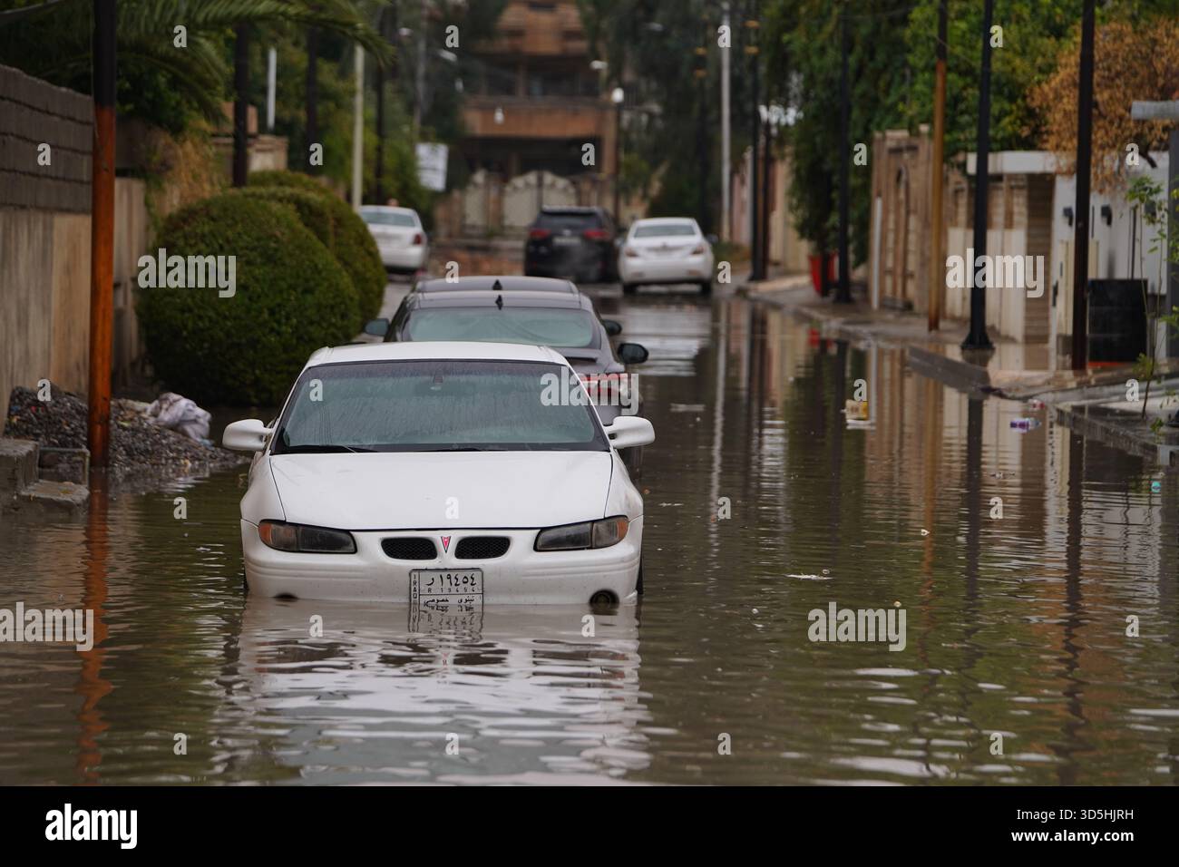 16 November 2025, Iraq, Mosul: Cars are parked in a flooded street in ...