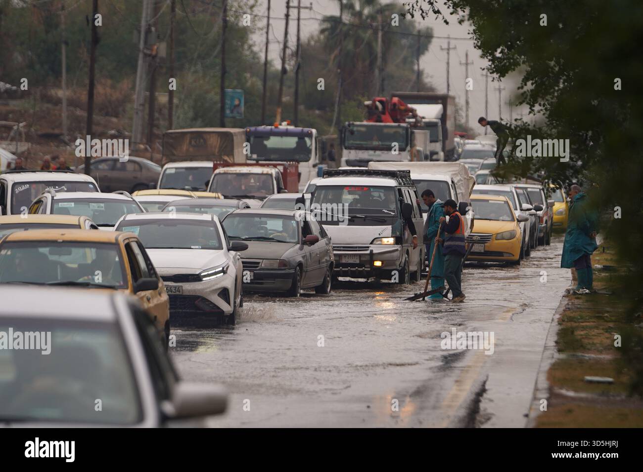 16 November 2025, Iraq, Mosul: Cars drive on a flooded street in Mosul ...