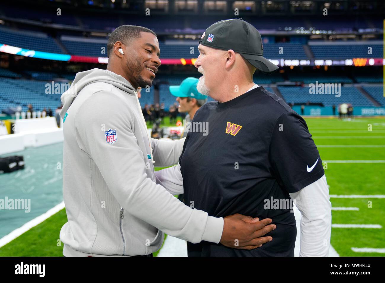 Washington Commanders head coach Dan Quinn, right, speaks with Miami ...