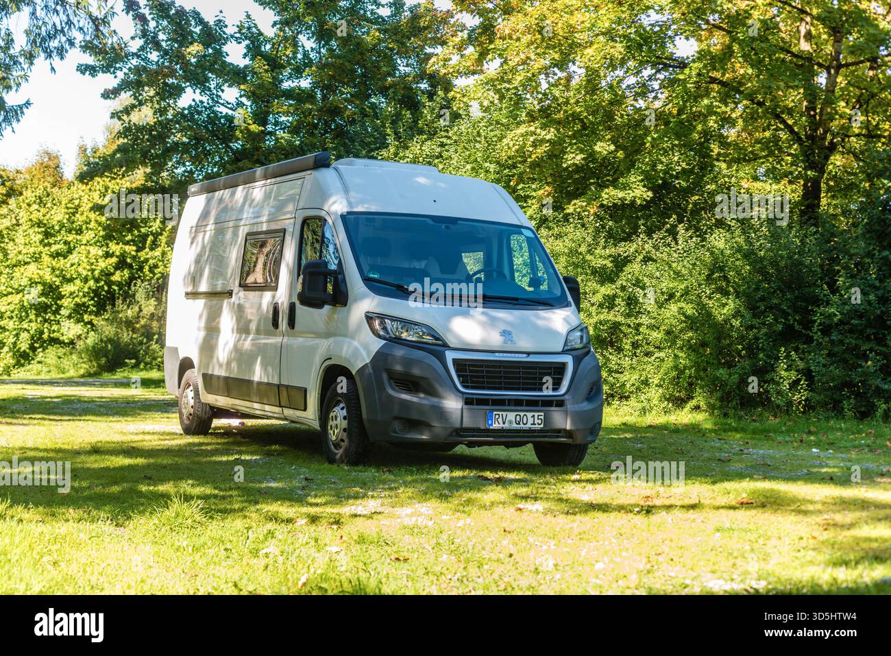 Ein Campingfahrzeug steht auf einer Wiese an einem Waldrand. Mit einem ...