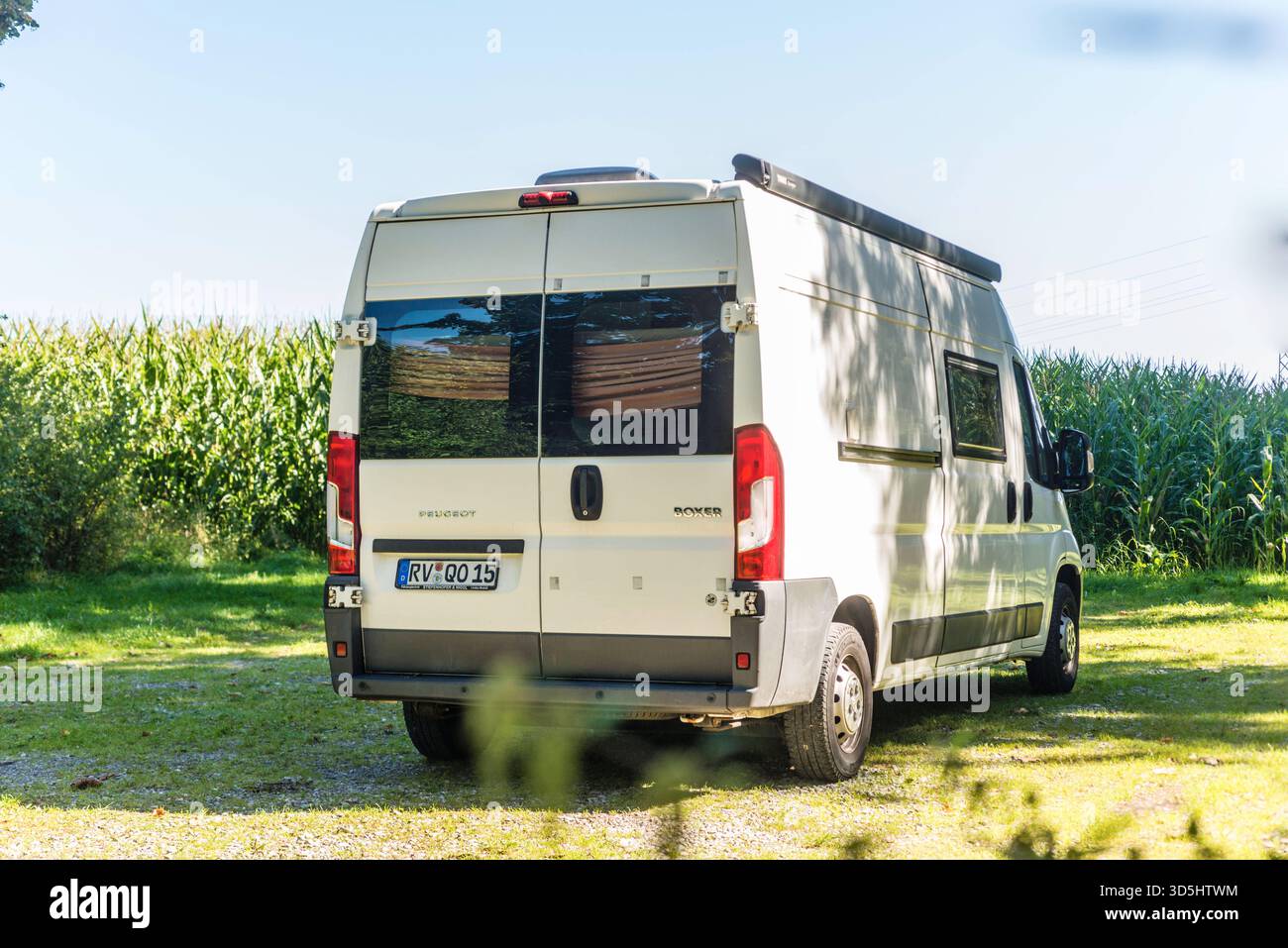 Ein Campingfahrzeug steht auf einer Wiese an einem Waldrand. Mit einem ...