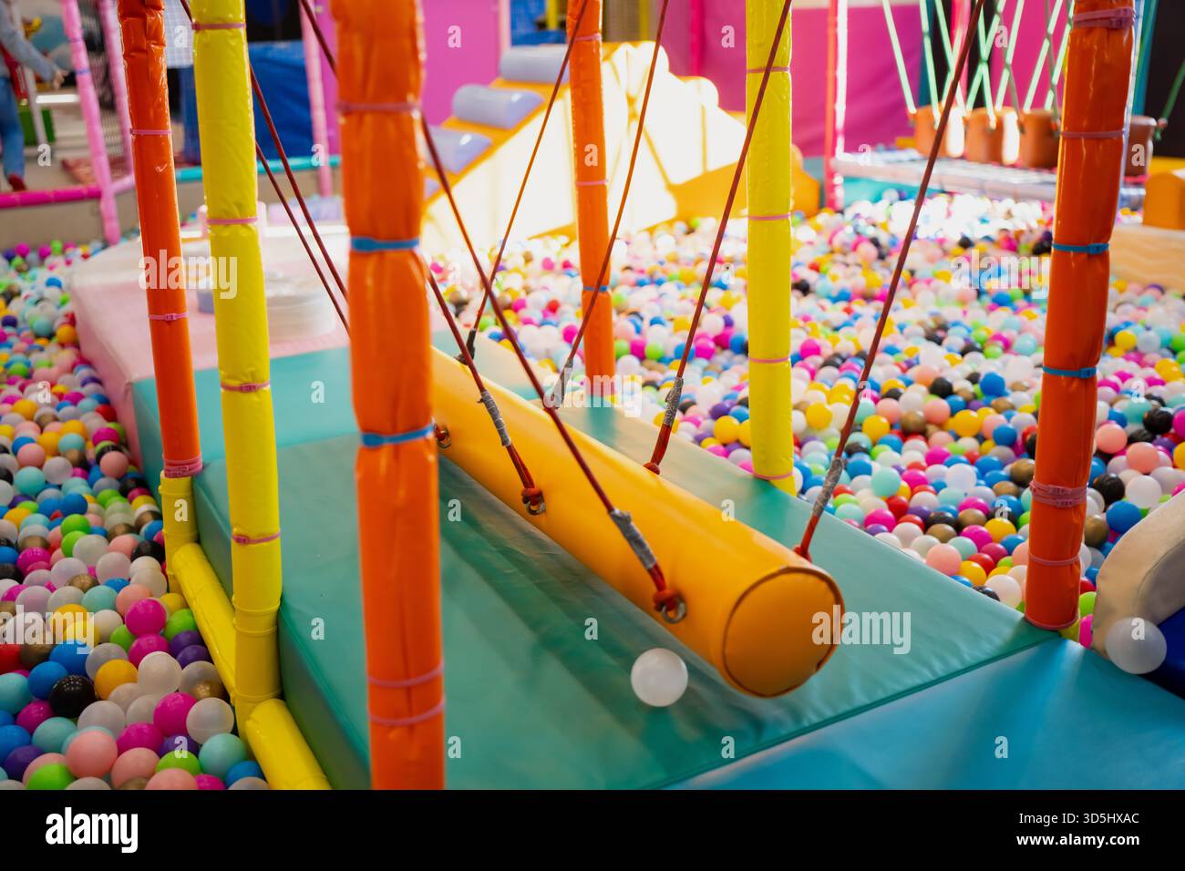 Colorful soft play balance bridge suspended above a ball pit inside an ...