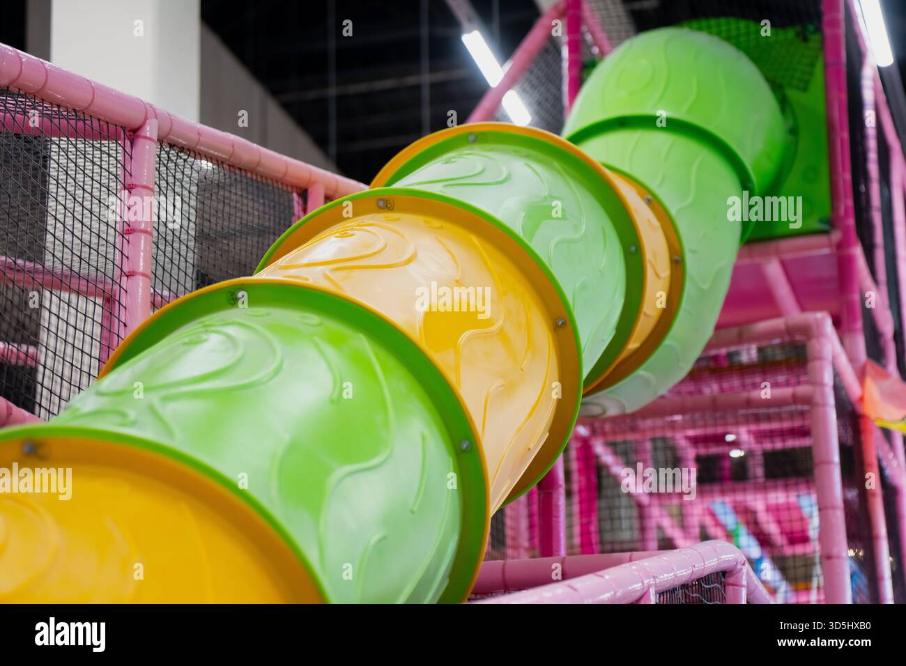Bright plastic spiral slide winding down a pink-framed indoor play ...