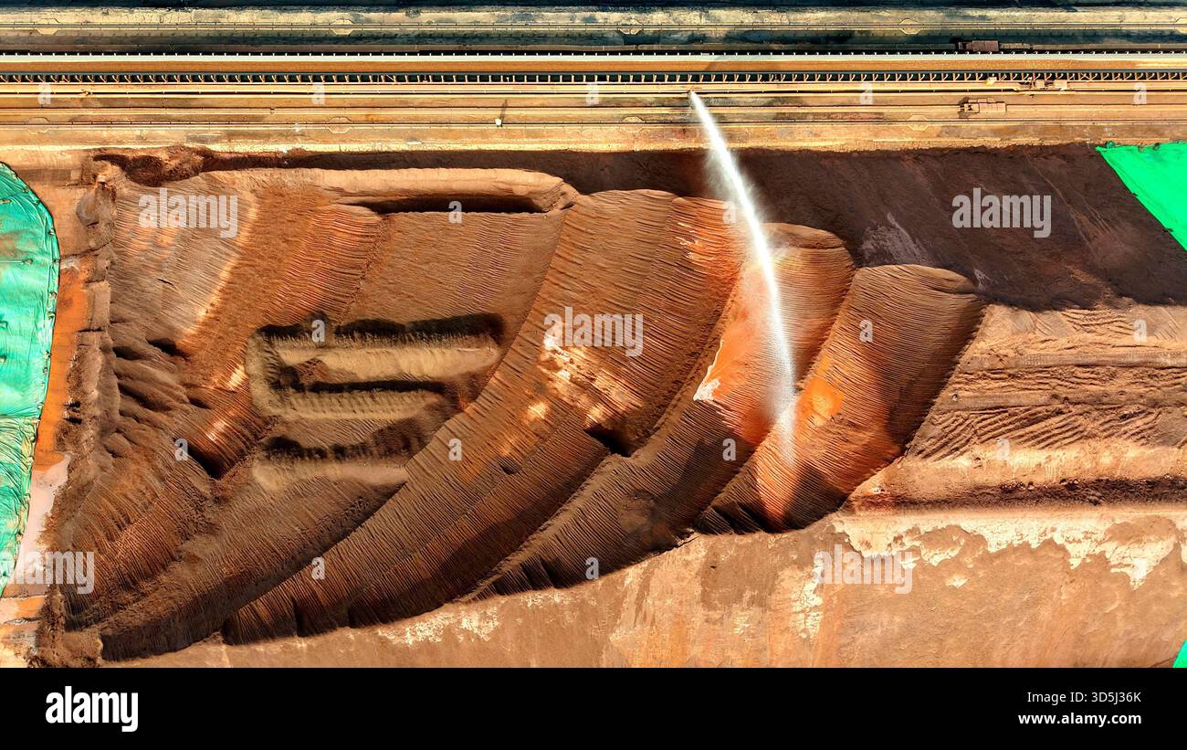 A nozzle sprays water on piles of iron ore to reduce dust at a port in ...