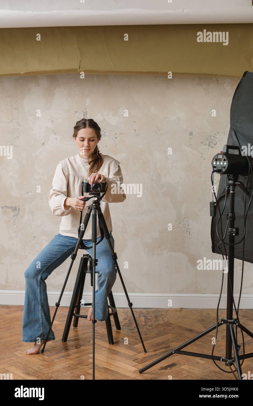 Female Photographer sitting on a stool in a photography studio setting ...