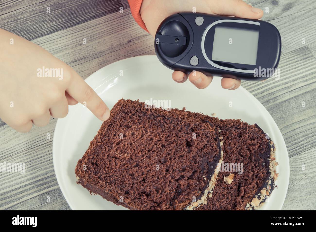Hand of child holding glucometer, sweet chocolate cake. Measuring and ...