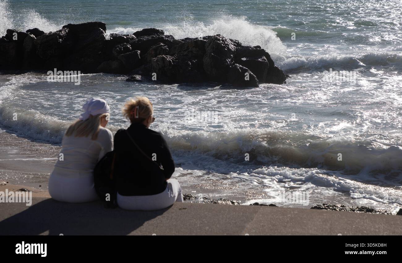 16 November 2025, Spain, Palma: People relax by the sea on the ...