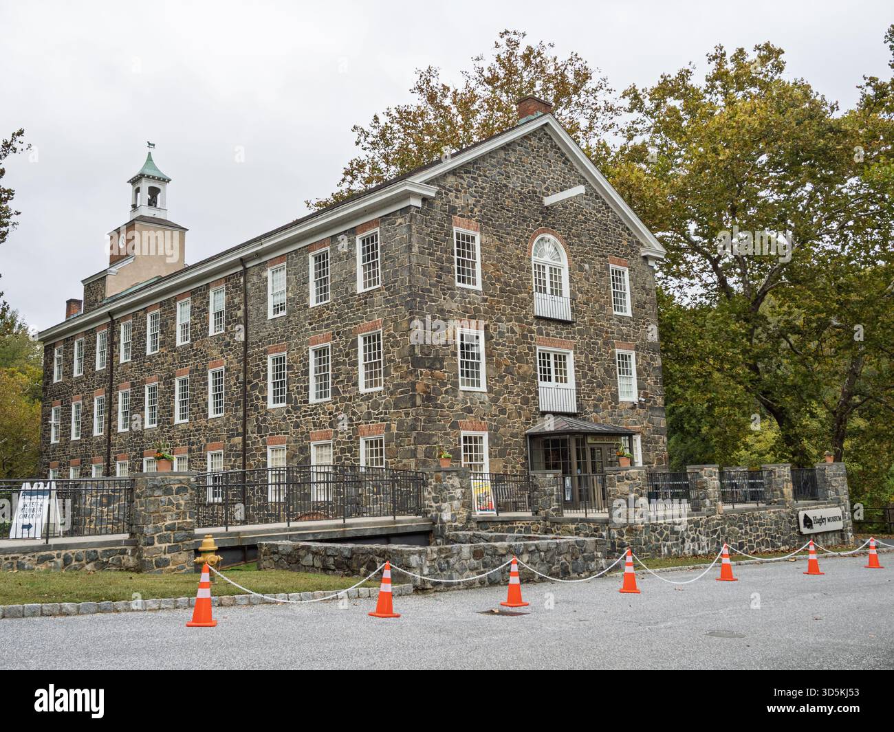 The multi-story stone factory building with white windows and a cupola ...