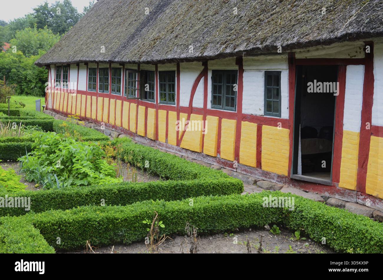 Half-timbered house with thatched roof by an older kitchen garden with ...