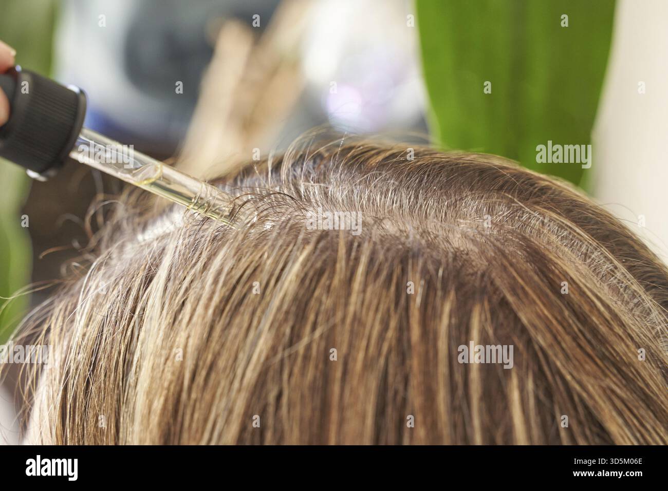 Female applying hair serum with dropper on scalp for hair care and ...