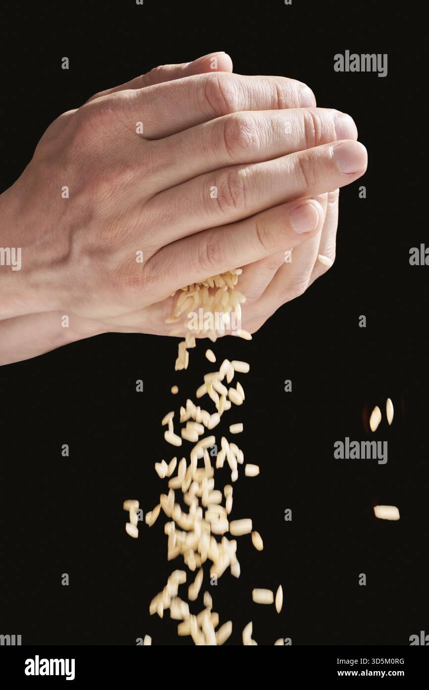 A hands hold a pile of rice, symbolizing charity, love, and hope. With ...