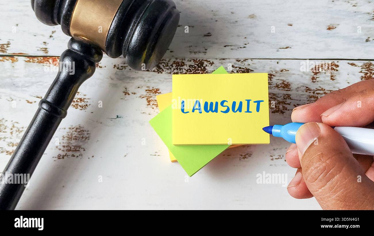 Hand Writing "Lawsuit" on a Sticky Note Next to a Judge's Gavel ...