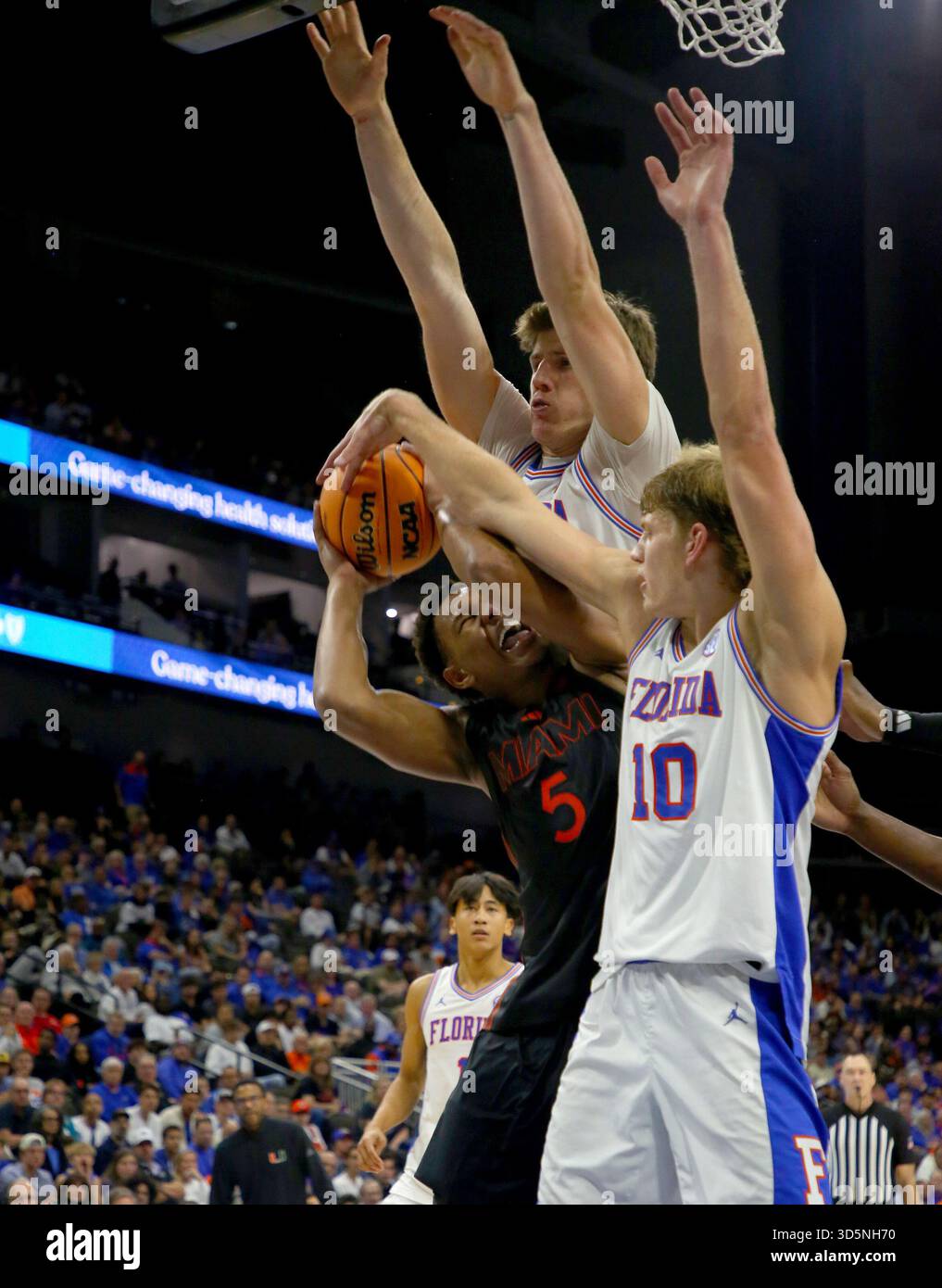 Miami's Malik Reneau, (5), goes up against Florida's Alex Condon and ...
