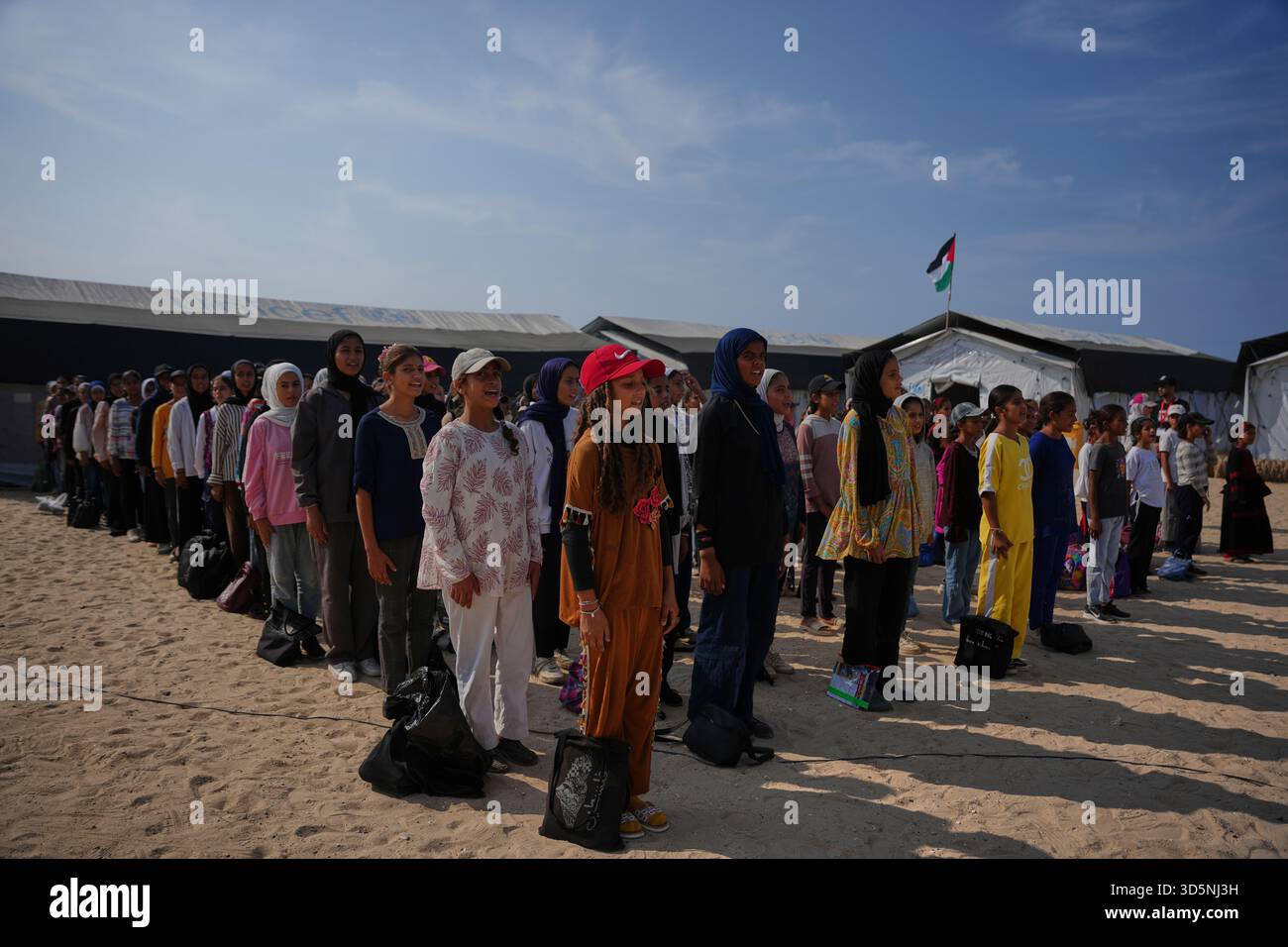 Students attend a morning assembly at a school set up on the beach in ...