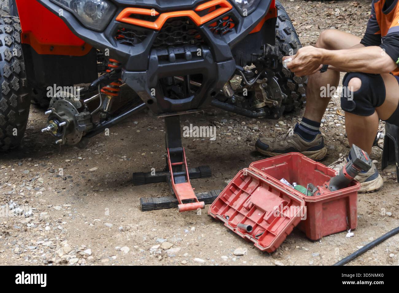 Focused mechanic doing DIY repair on red off road vehicle. man works ...