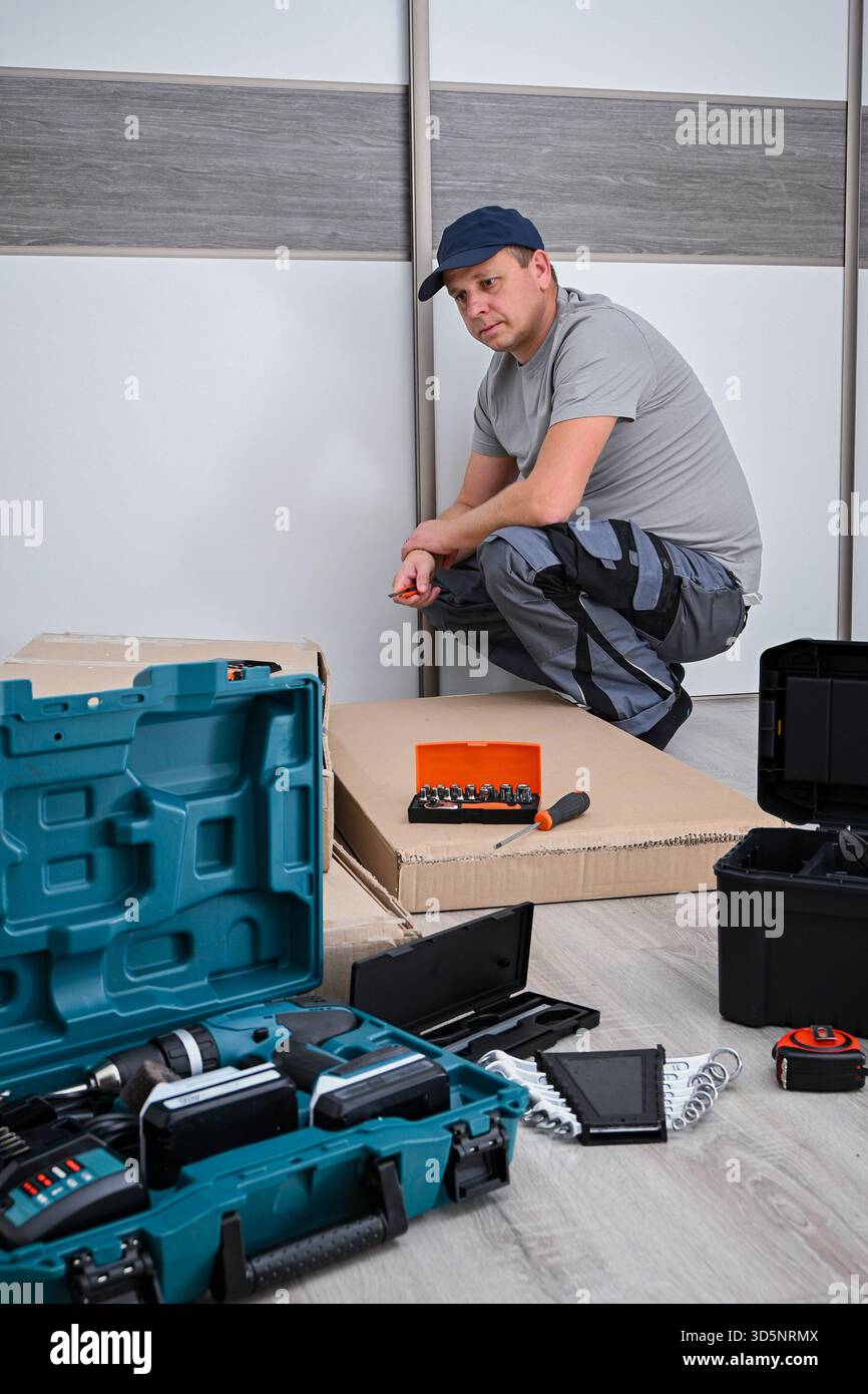 Man feeling frustrated and confused while kneeling by an unassembled ...