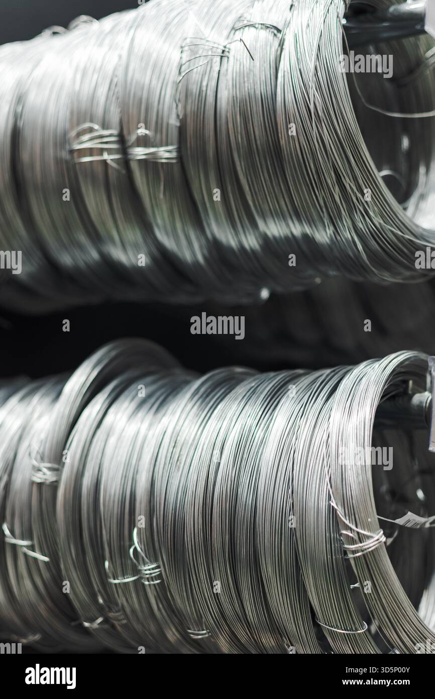 Tightly wound coils of industrial metal wire stacked in a warehouse ...