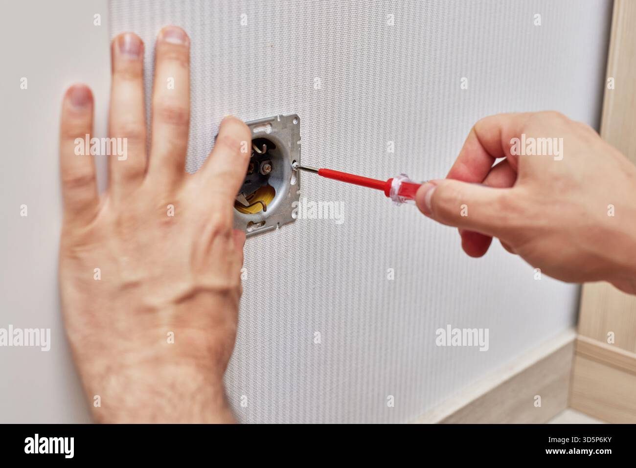 male hands installing electrical wall outlets with a screwdriver at ...